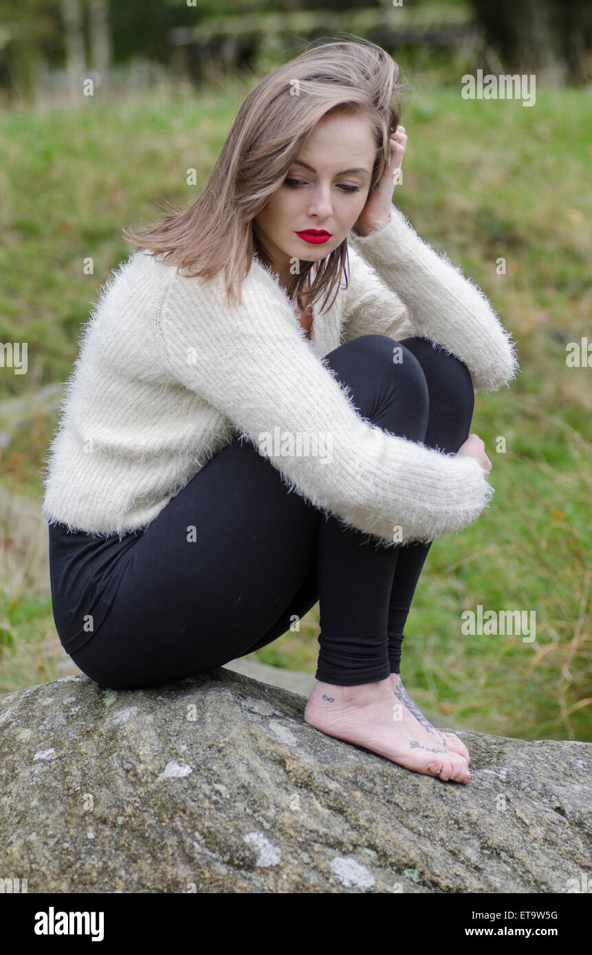 Young woman sat on the rocks Stock Photo - Alamy