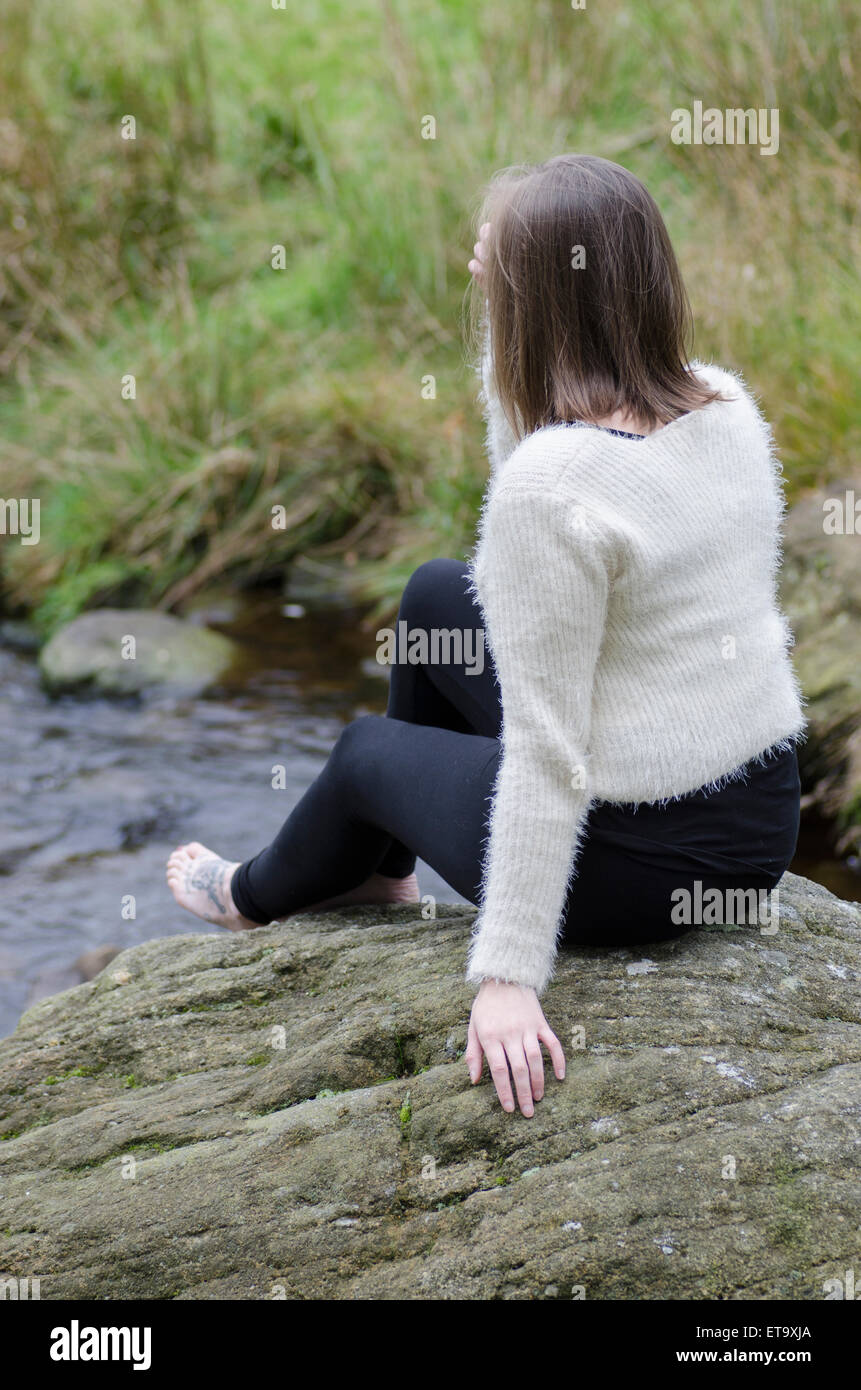 Young woman sat on the rocks Stock Photo - Alamy
