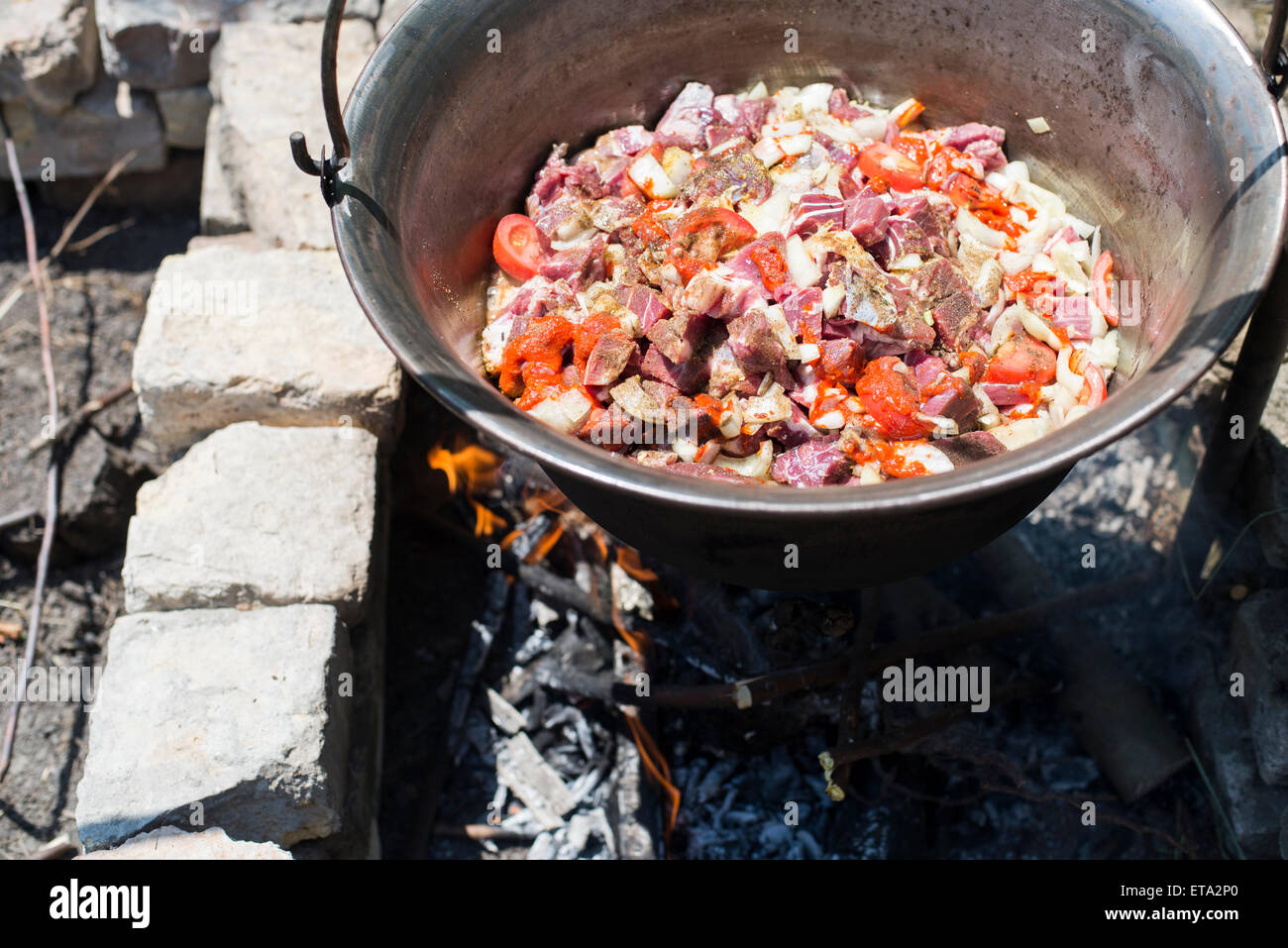 Hungarian traditional cauldron with beef stew cooking on fire outdoors ...