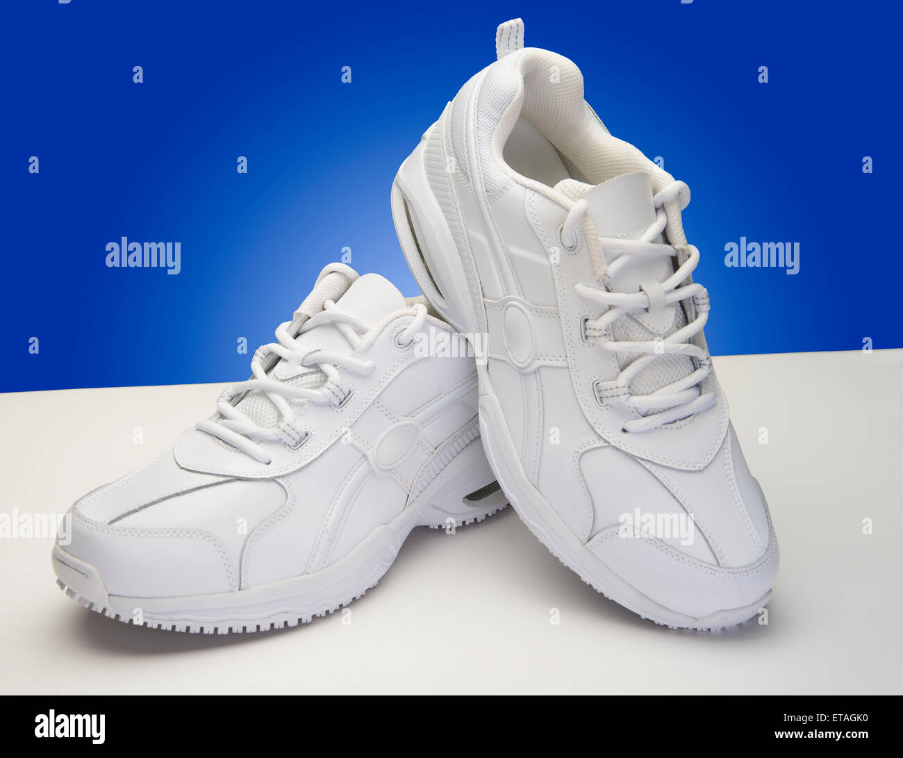 White athletic shoes with blue background Stock Photo - Alamy