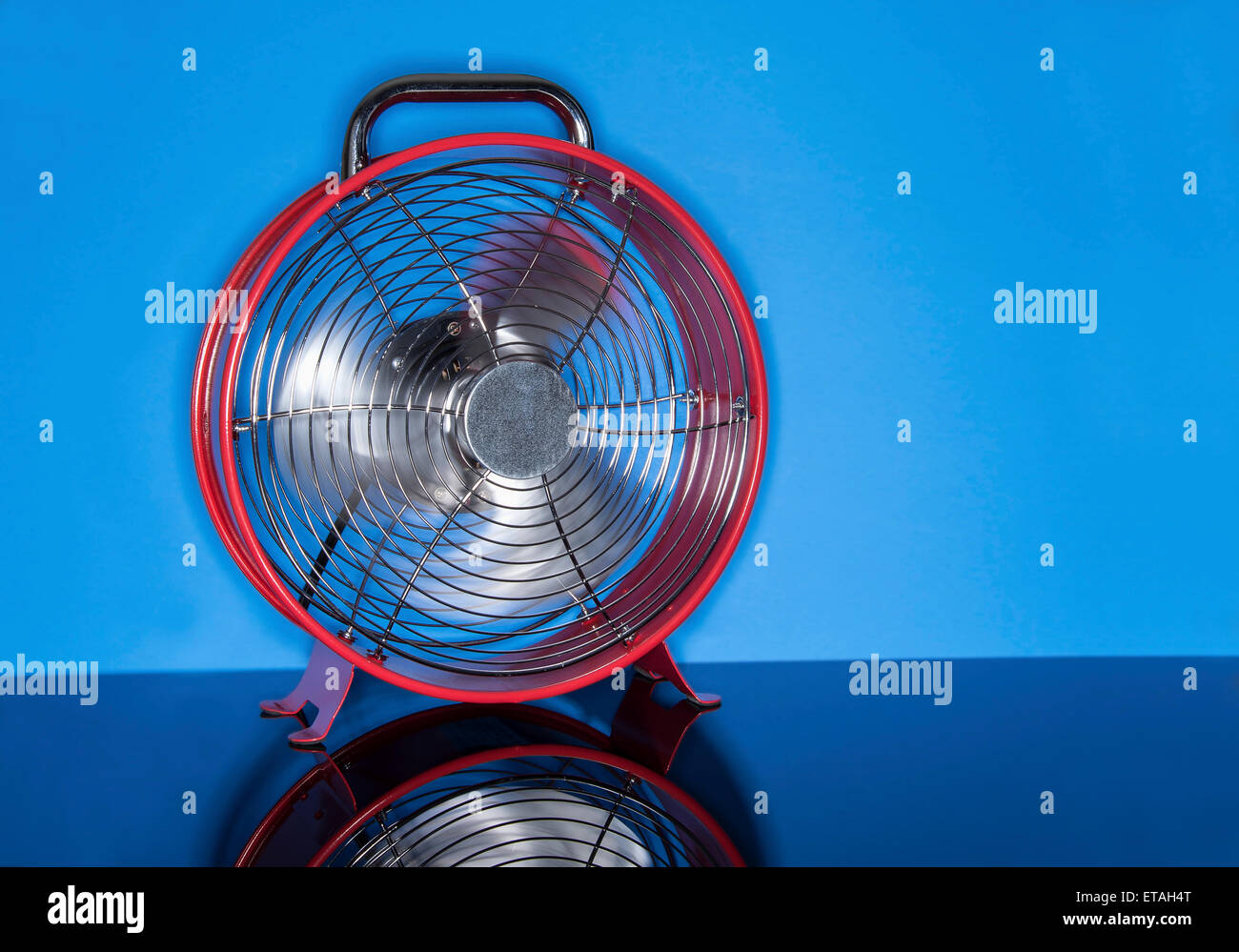Red Fan on blue background for summer cooling Stock Photo - Alamy