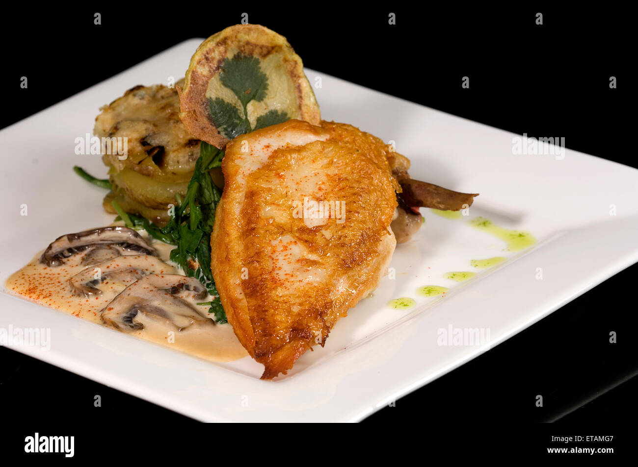 A chicken entree on a white plate served with mushrooms and potatoes ...