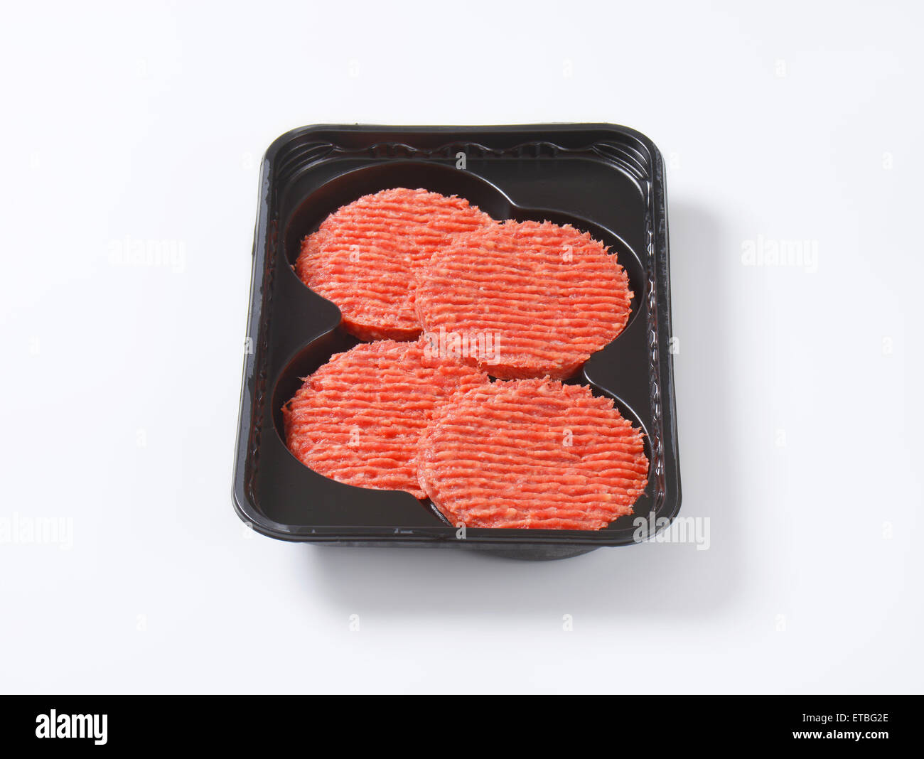 four raw hamburger patties on black plastic tray Stock Photo - Alamy