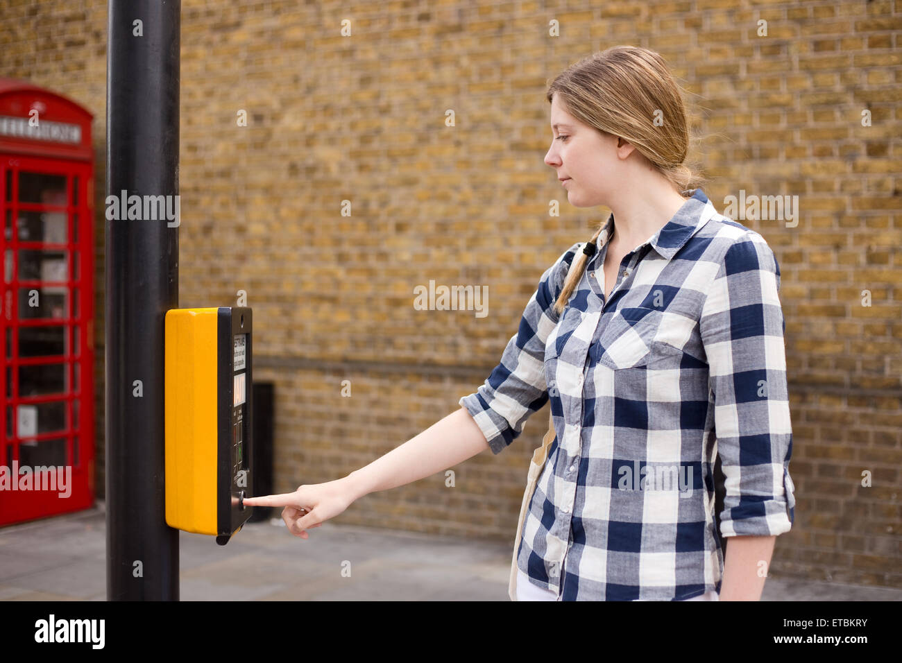 a young woman pressing the button to cross the road Stock Photo - Alamy