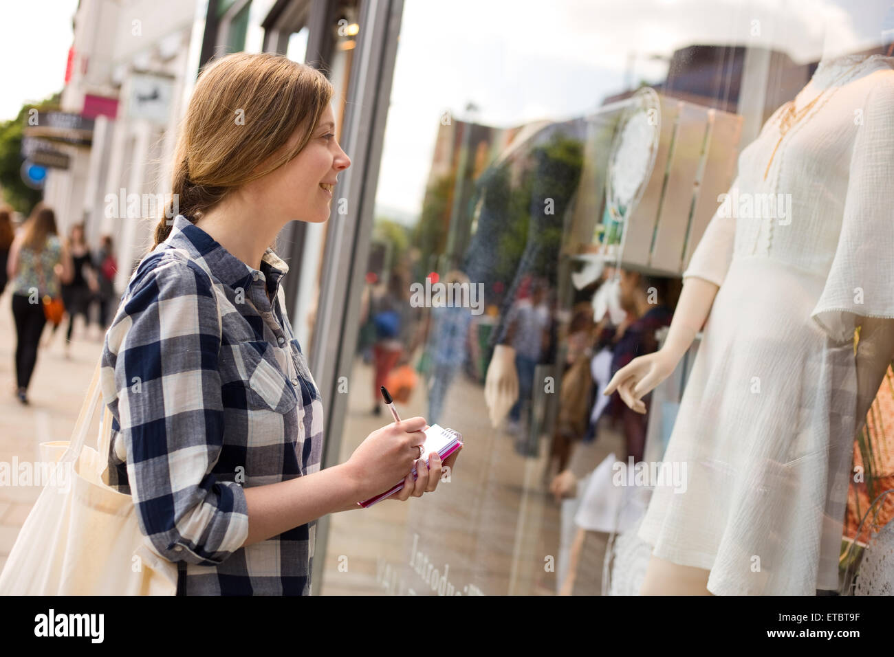 young woman taking notes looking in a shop window Stock Photo - Alamy