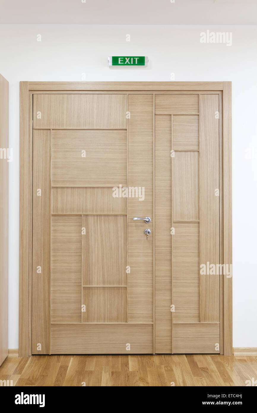 large wooden door on white wall with exit sign Stock Photo - Alamy