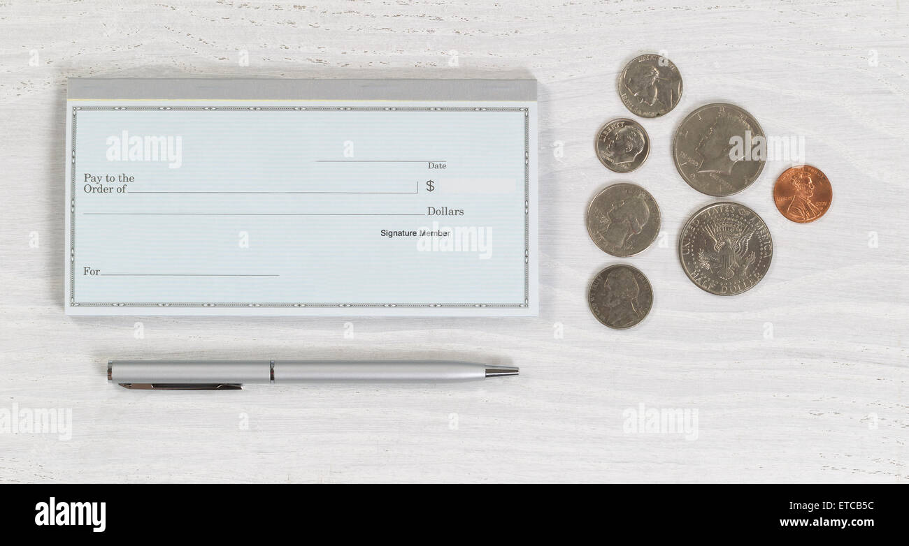 Close up of blank checkbook, silver pen and coins on white wooden ...