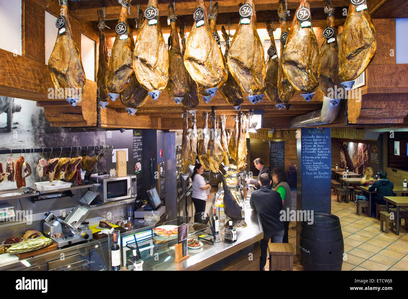 Patrons in a bar in Pamplona, Spain with jamon ham hanging from the ...