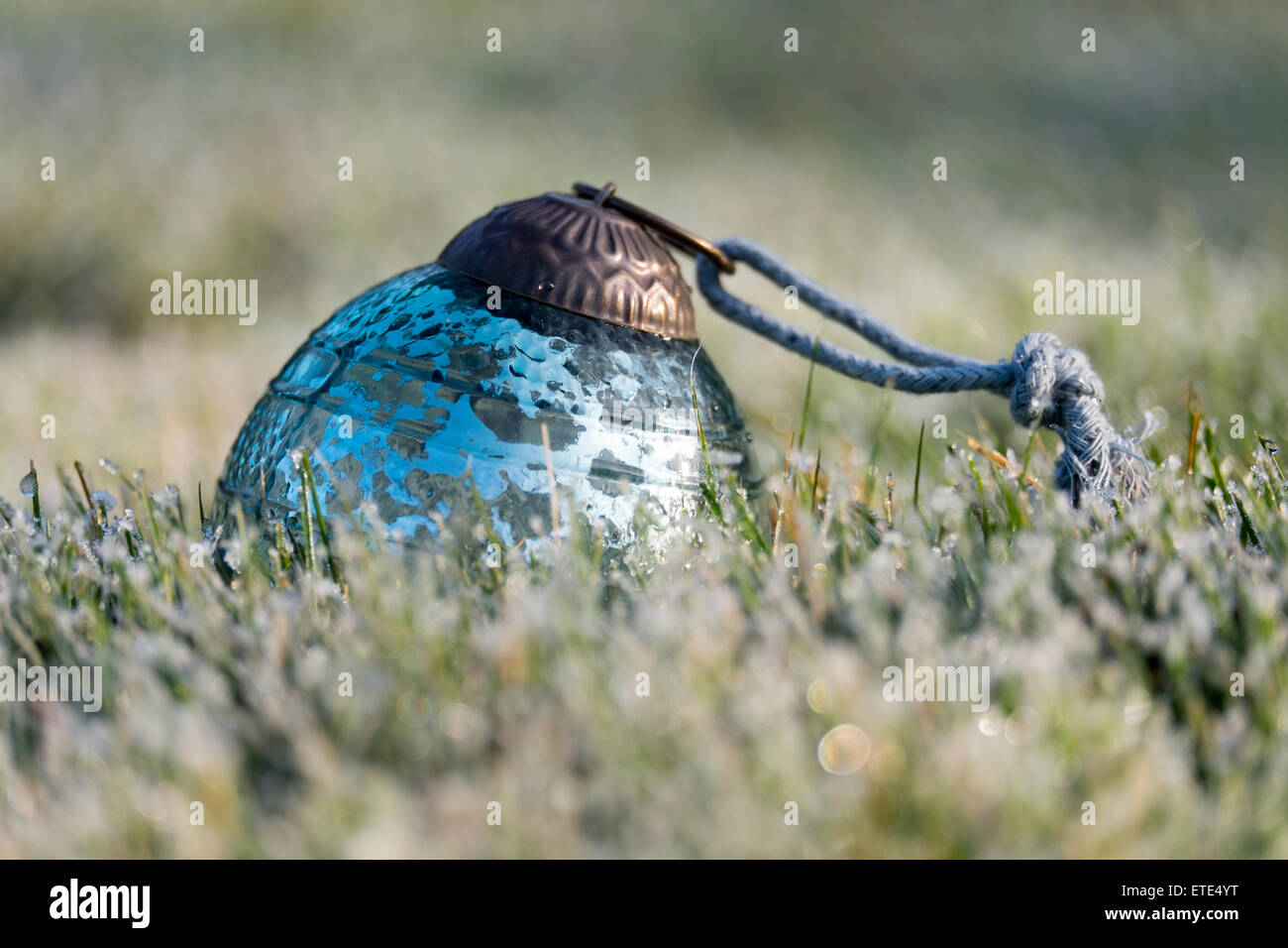 Christmas bauble in the grass on a cold, bright morning, with frost and ...