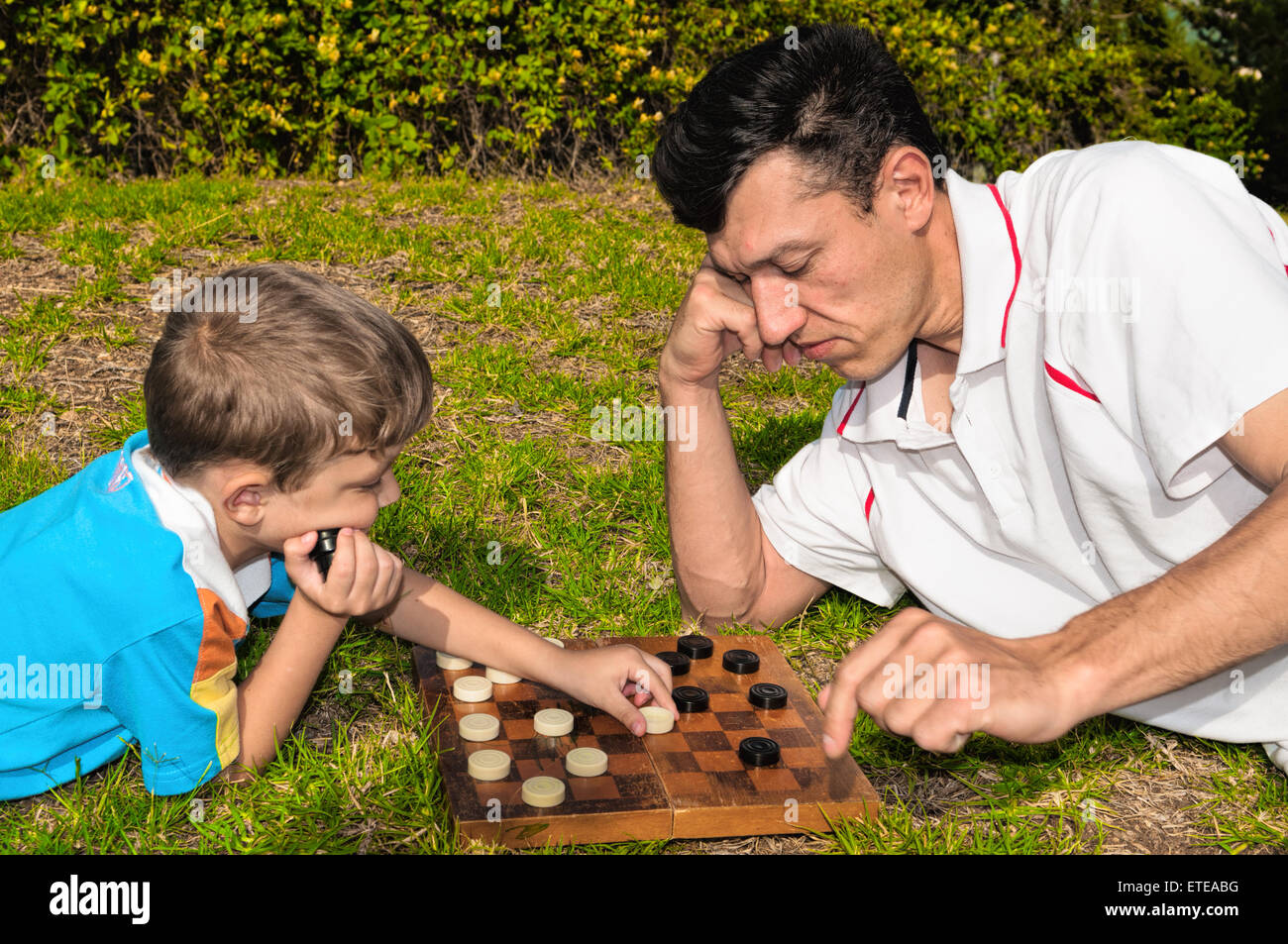 Father and son playing checkers on the grass in a city park Stock Photo ...
