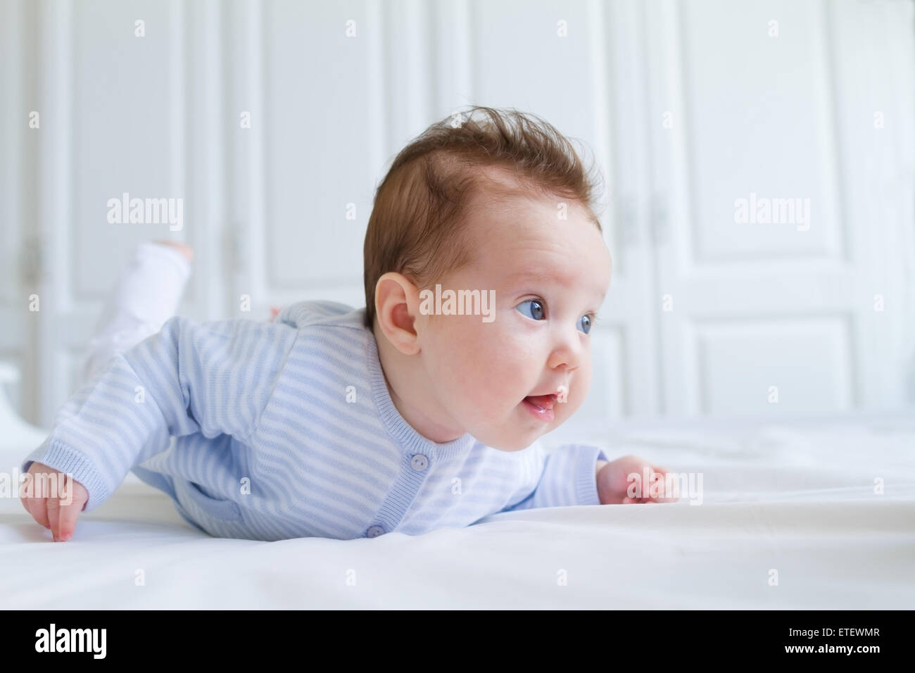 Baby tummy time, wearing blue clothes in a white nursery Stock Photo ...