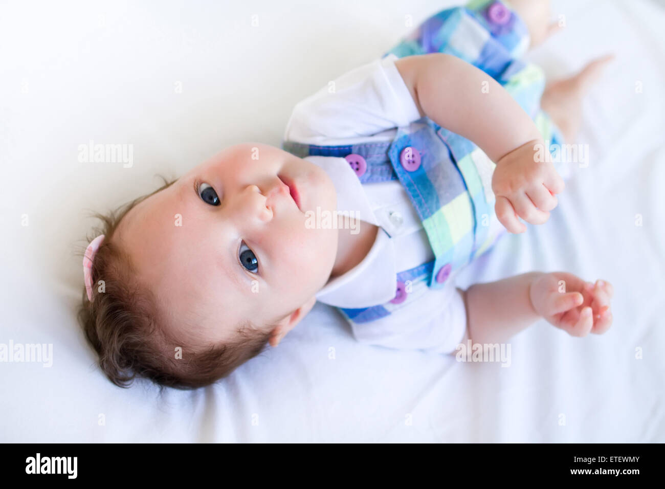 Adorable brunette baby girl in purple overalls Stock Photo - Alamy