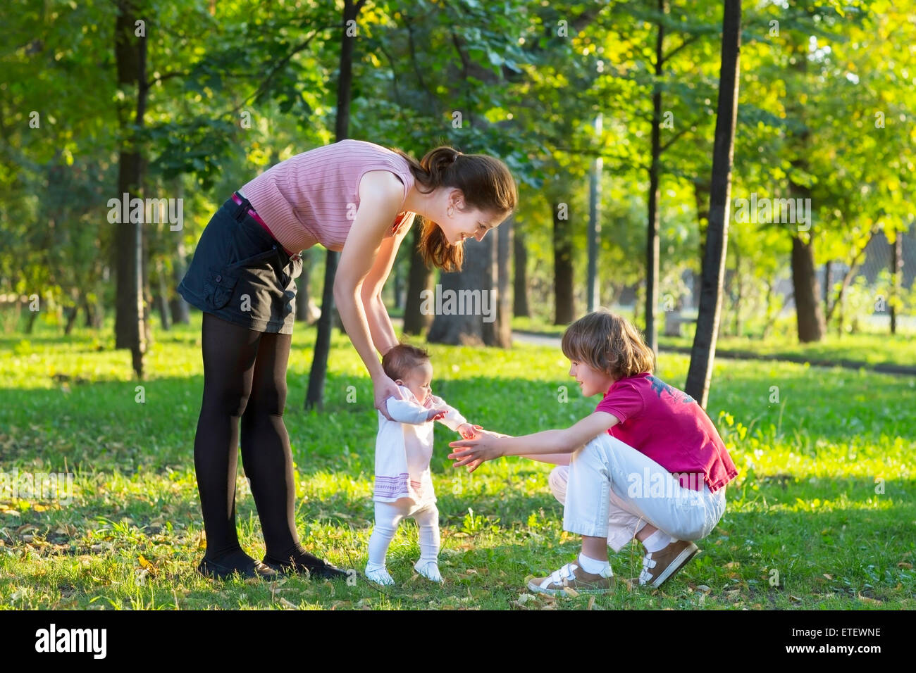 Baby girl first steps with mother and brother in a park Stock Photo - Alamy