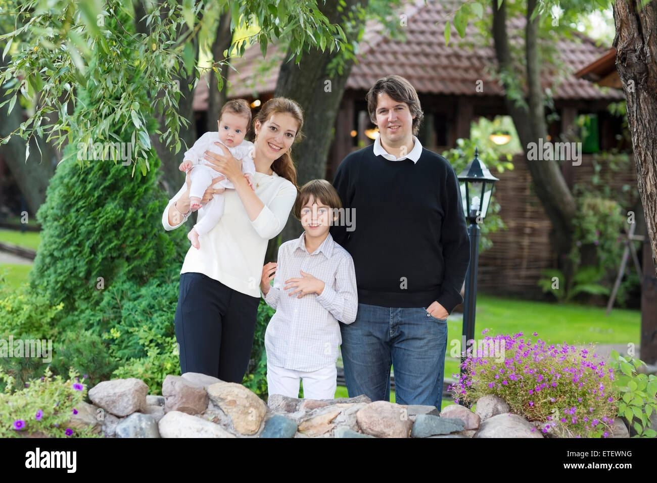 Young beautiful couple with two kids in a garden Stock Photo - Alamy