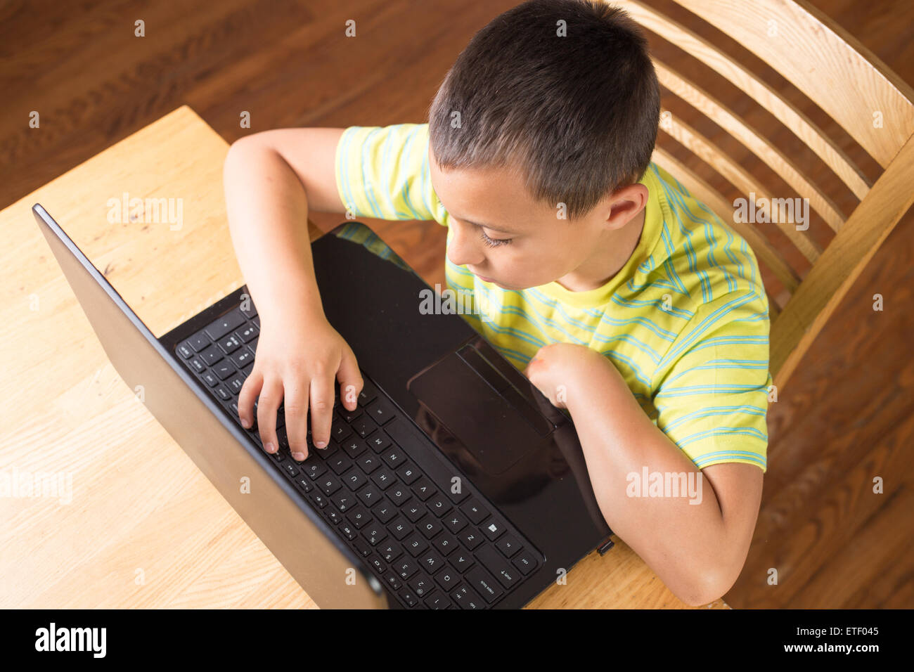 A young boy is playing on a laptop in the kitchen Stock Photo - Alamy