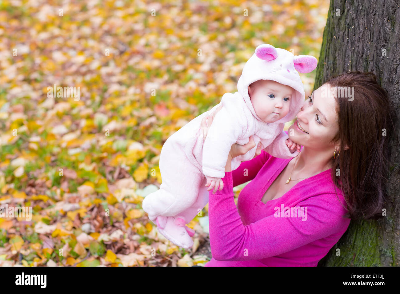 Portrait of a young mother holding her baby daughter sitting under a ...