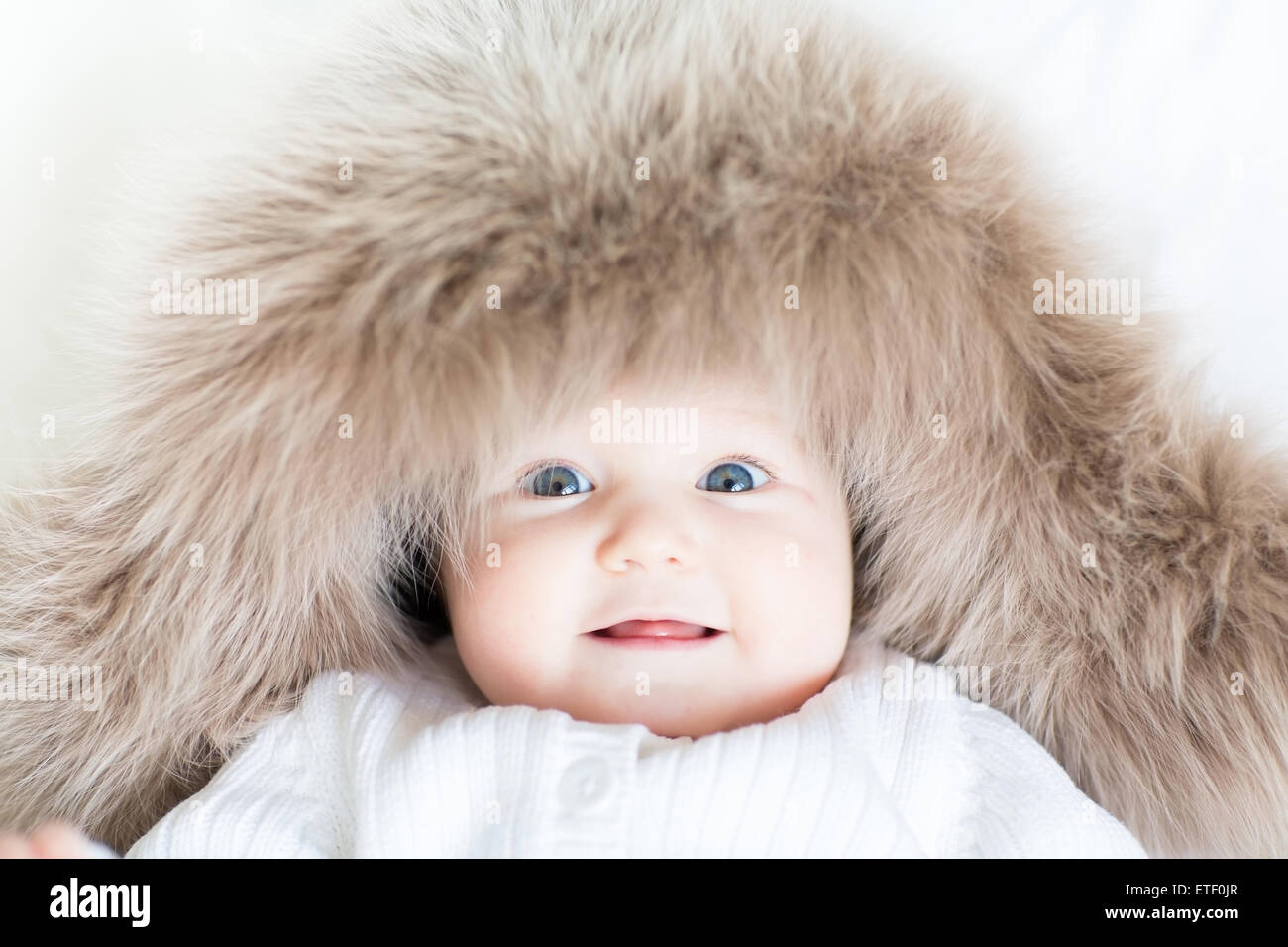 Sweet little baby in a huge fur hat Stock Photo - Alamy