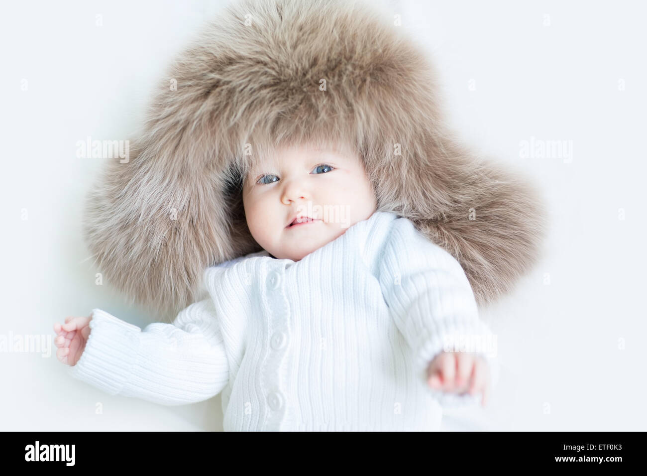 Curious little baby in a huge fur hat Stock Photo - Alamy