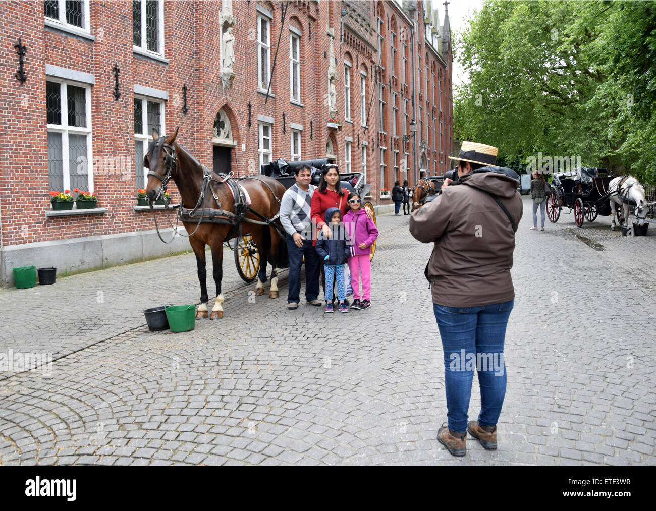 A female horse and carriage driver takes a photo of her passengers in ...