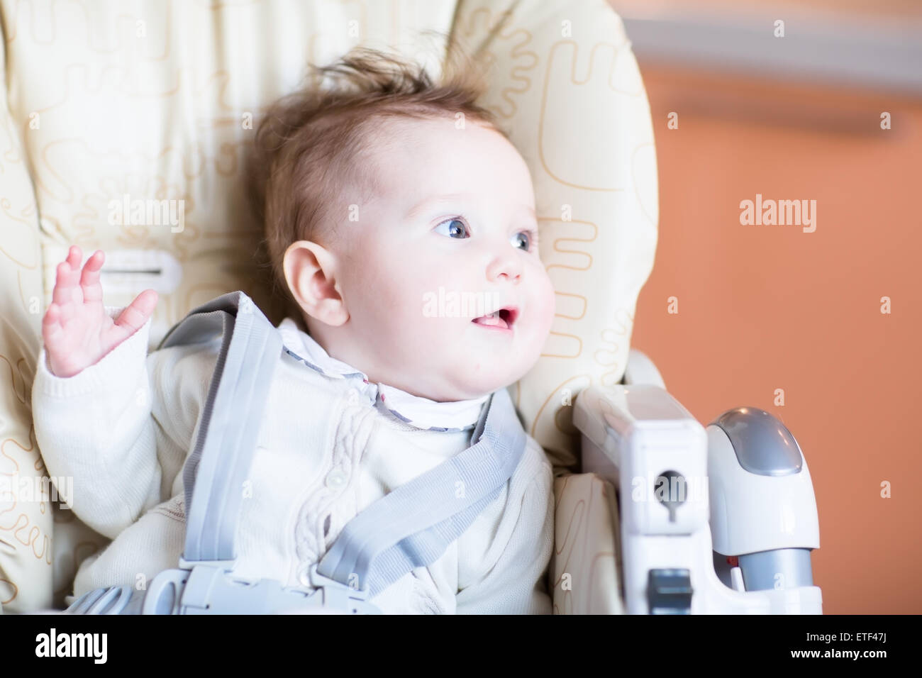 Adorable little girl sitting in a high chair in the kitchen Stock Photo ...