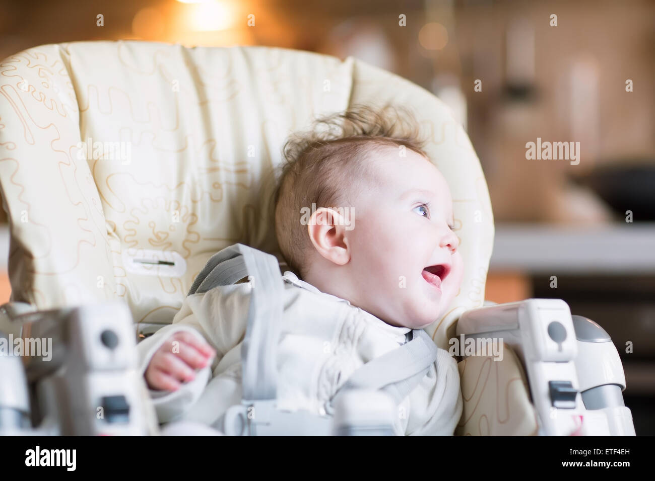 Adorable little girl sitting in a high chair in the kitchen Stock Photo ...