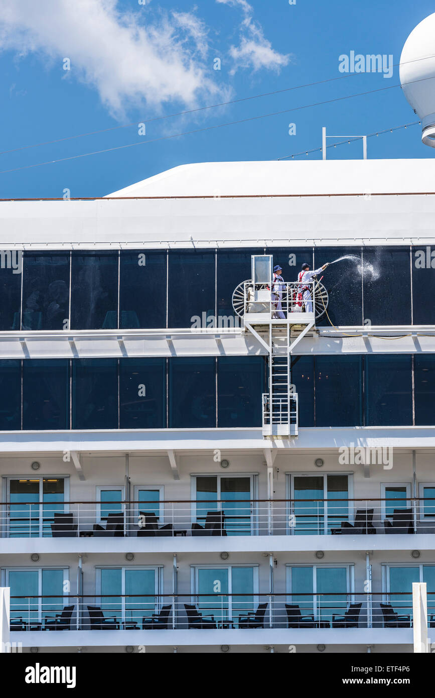Two workers cleaning the windows on a raised platform of a cruise ship ...