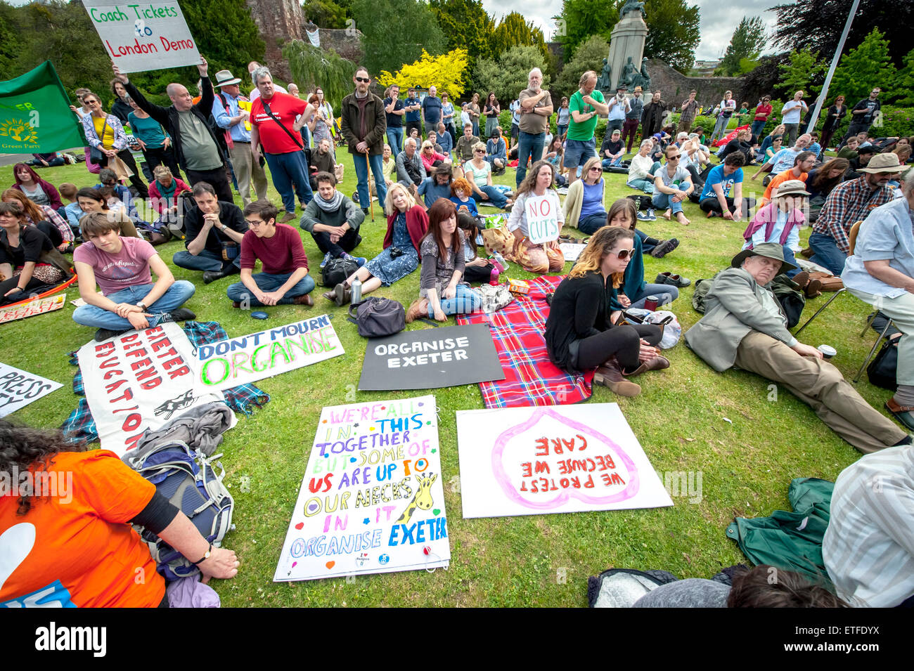 Exeter, Devon, UK. 13th June, 2015. The crowd sit woth placards ...