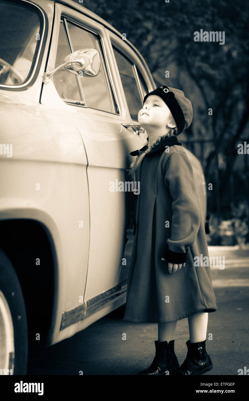 Cute little girl dressed in retro coat posing near oldtimer car, sixties Stock Photo - Alamy