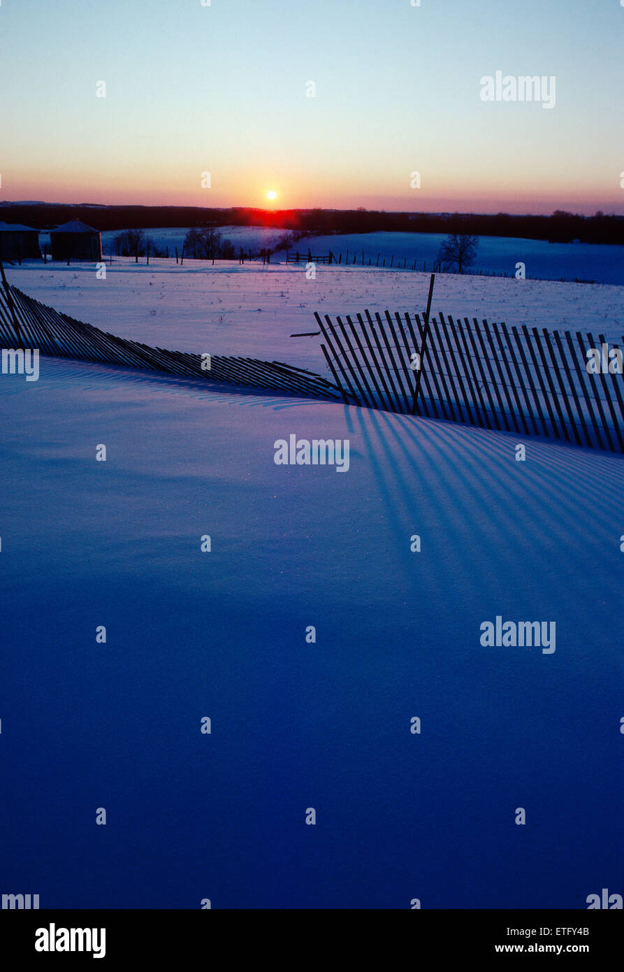 Sunset winter view of blowing snow and frozen farm fields, upstate New ...