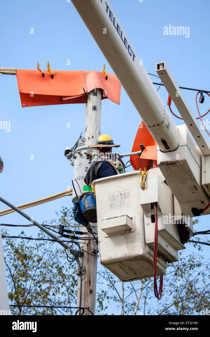 A lineman uses a cherry picker lift bucket to repair electric wires ...