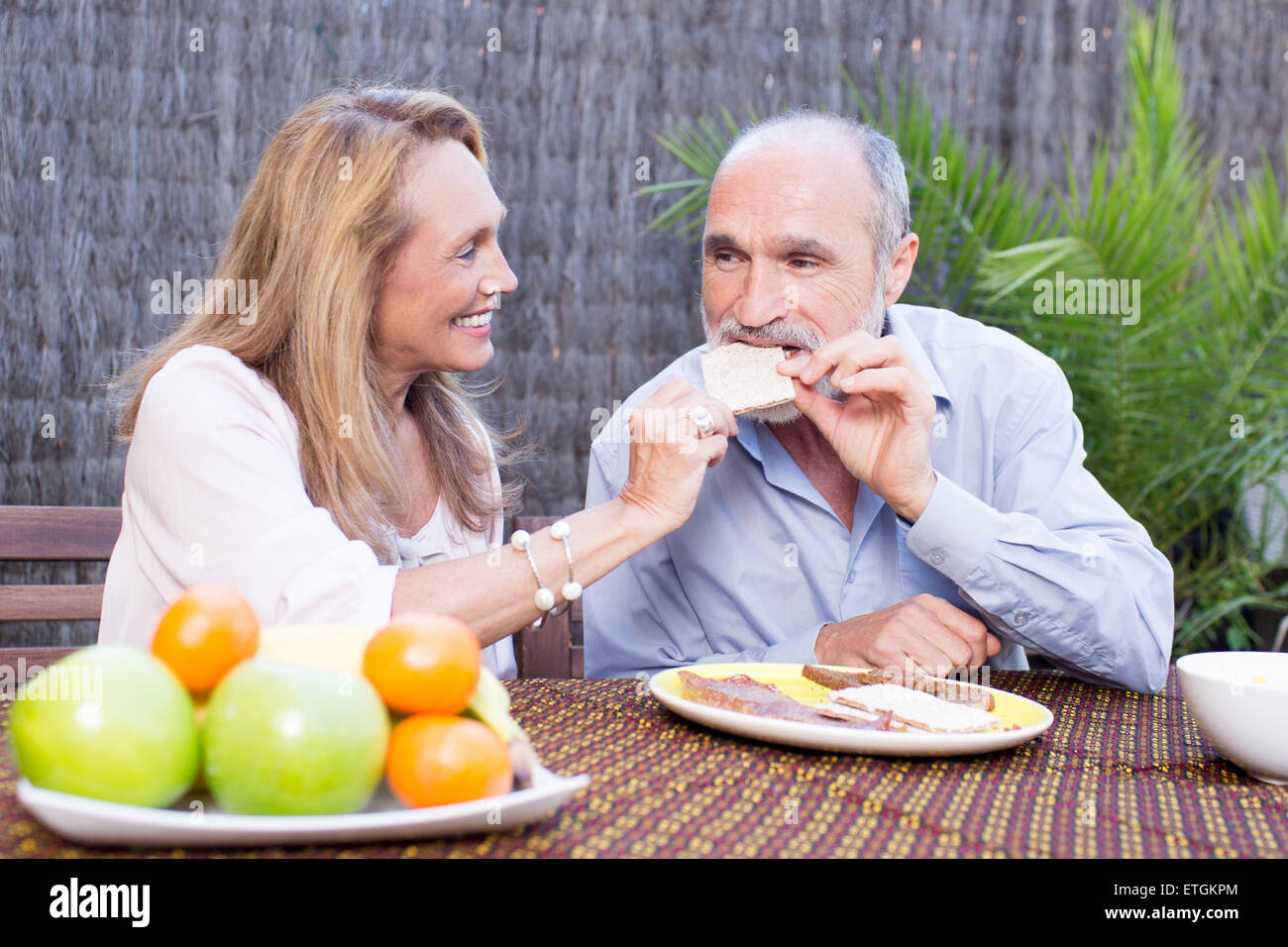 Elderly couple eating snacks in garden Stock Photo - Alamy