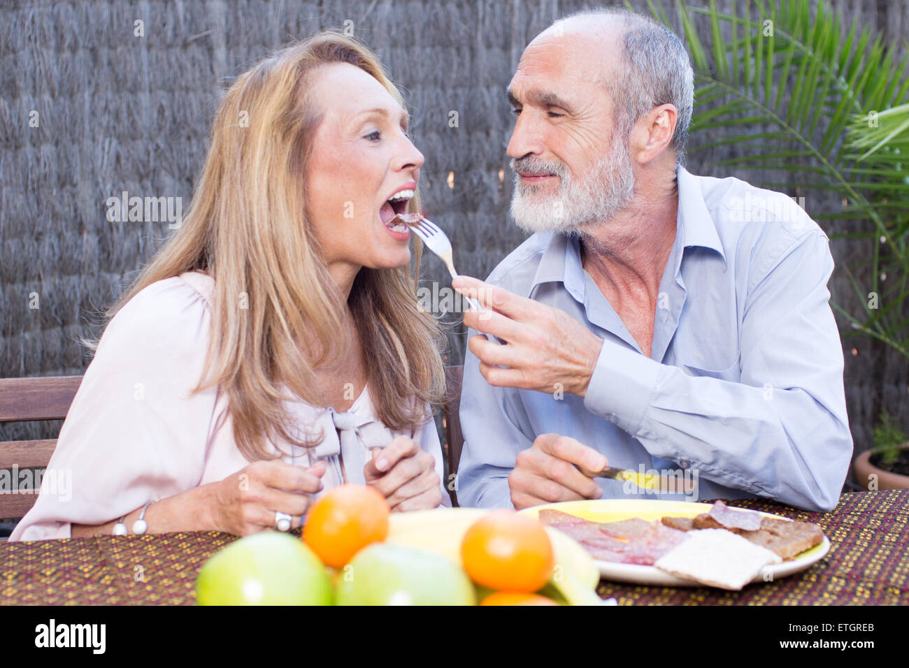 Elderly couple eating snacks in garden Stock Photo - Alamy