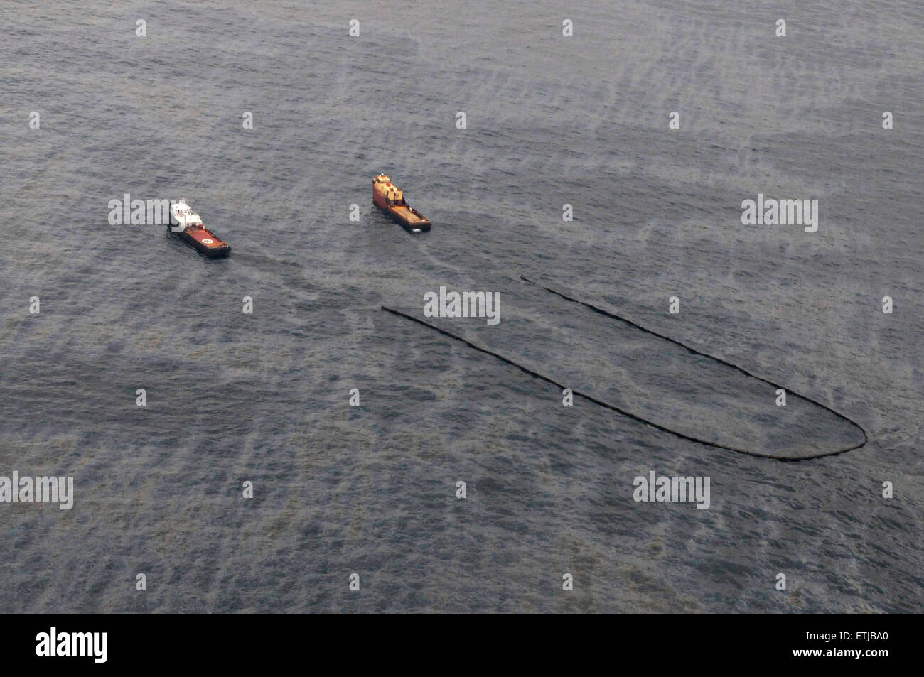 Clean up crews conduct use fire resistant boom to gather crude oil for ...