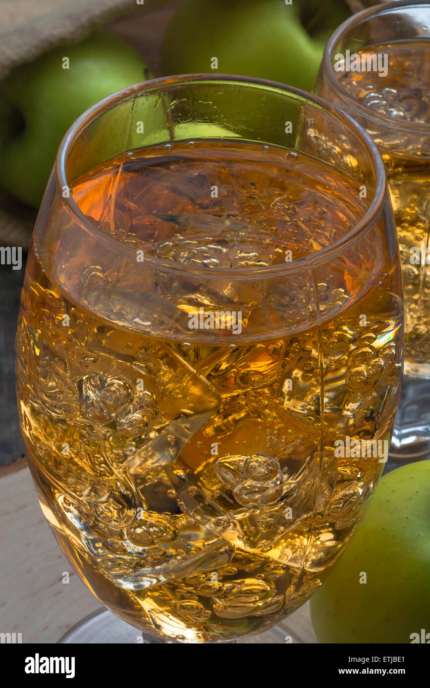 Glass of cold refreshing apple cider with ice cubes and apples on ...