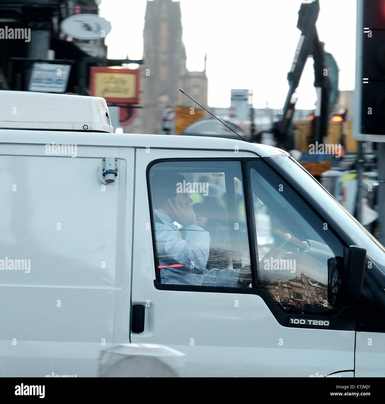 A white van driver talks on his mobile phone whilst driving through ...