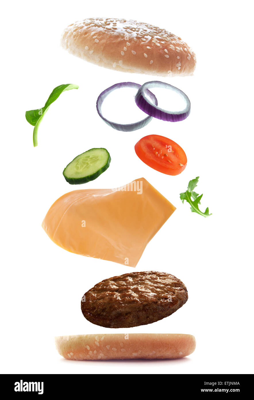 Burger ingredients falling into place to create a sandwich over a white ...