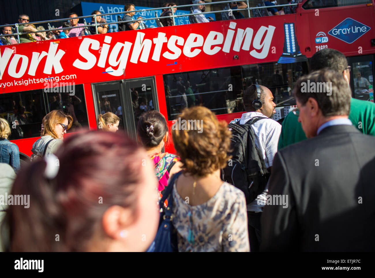 A tourism bus makes a turn in front of pedestrians crossing an ...