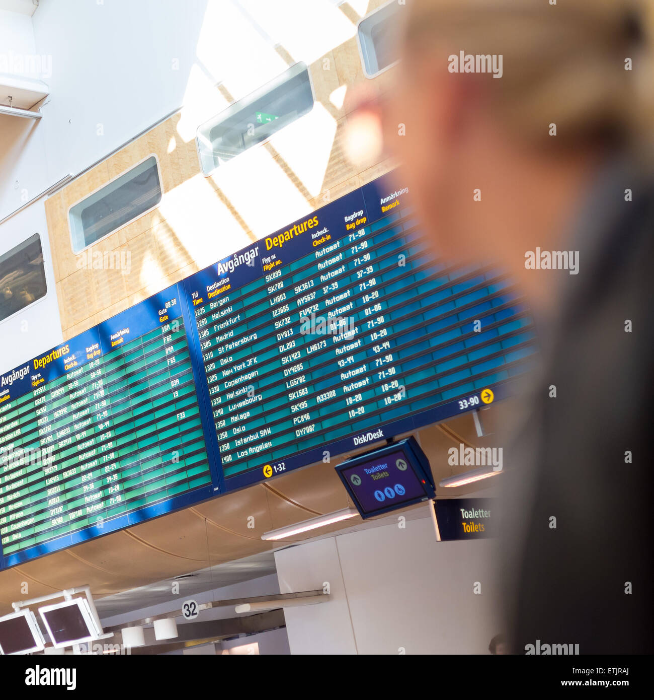 Female traveller checking flight departures board Stock Photo - Alamy