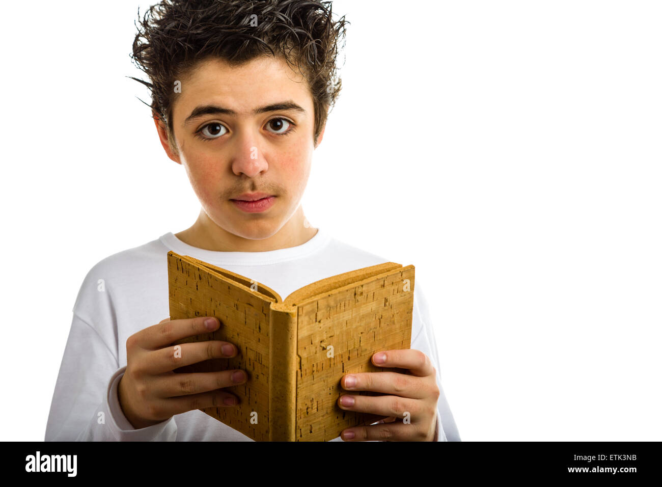 A handsome Hispanic boy reads with serene eyes a brown blank book made ...