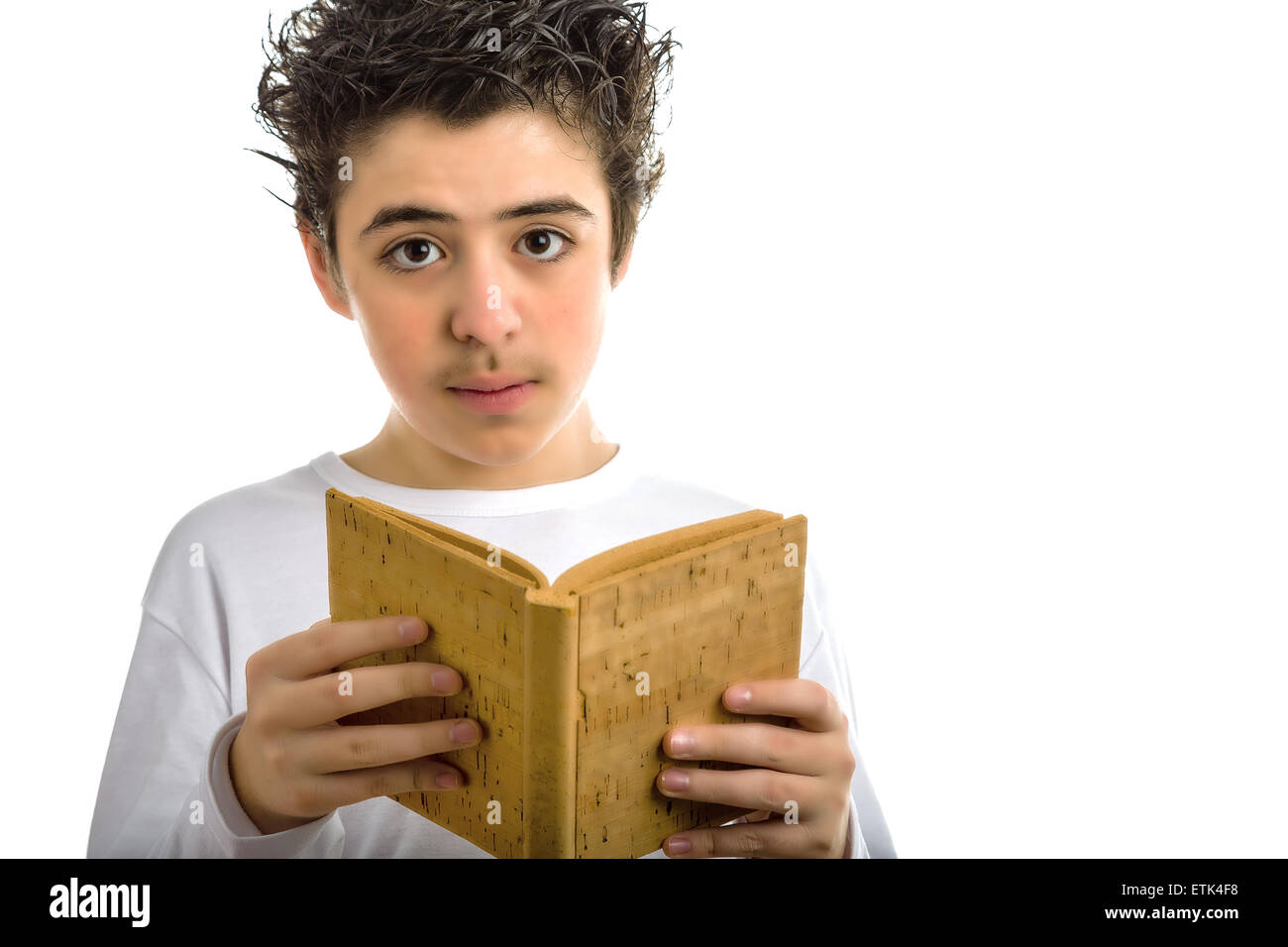 A handsome Hispanic boy reads with serene eyes a brown blank book made ...