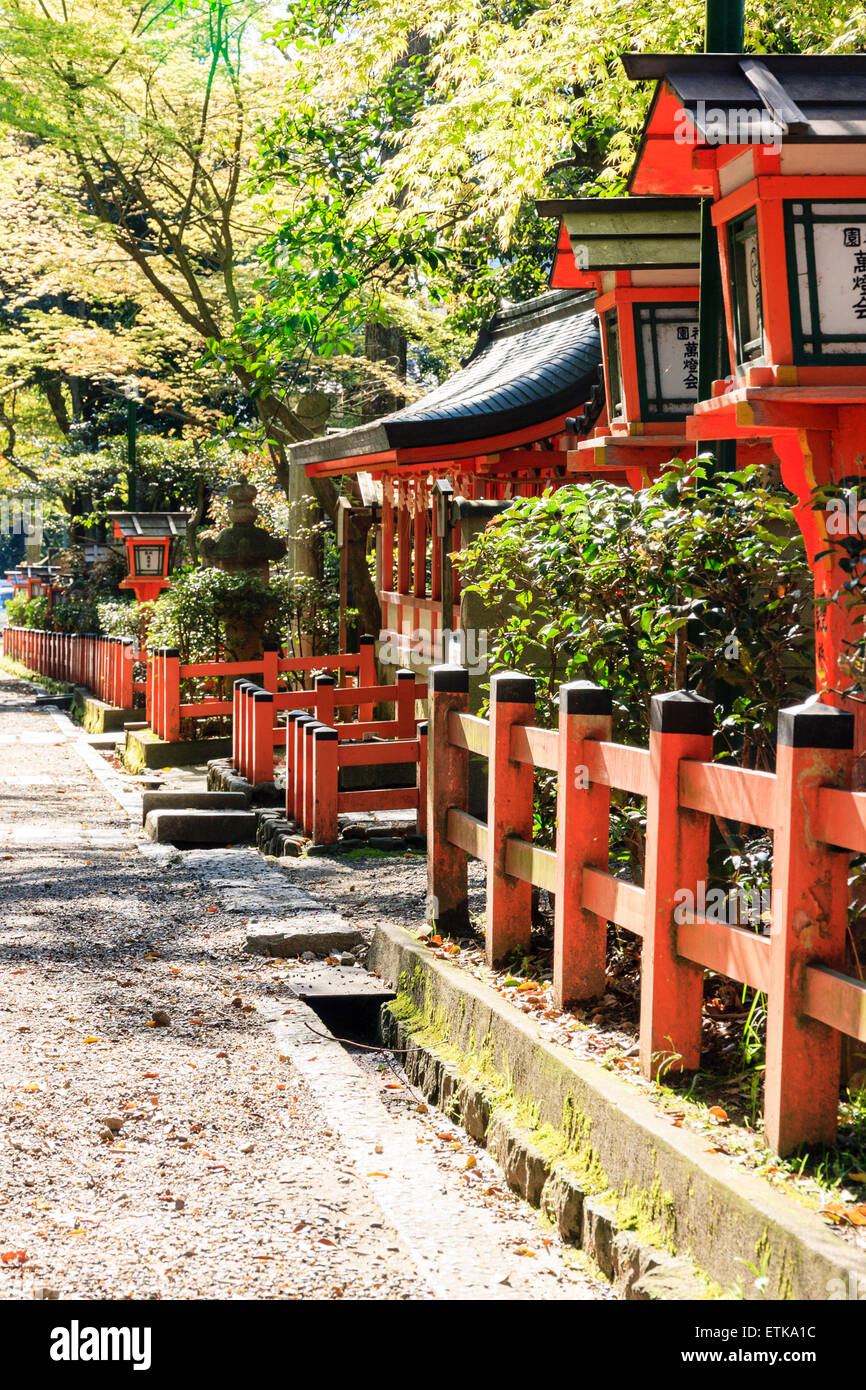 Yasaka Shrine in Kyoto. Sunlit tree-lined stone lane with vermilion and ...