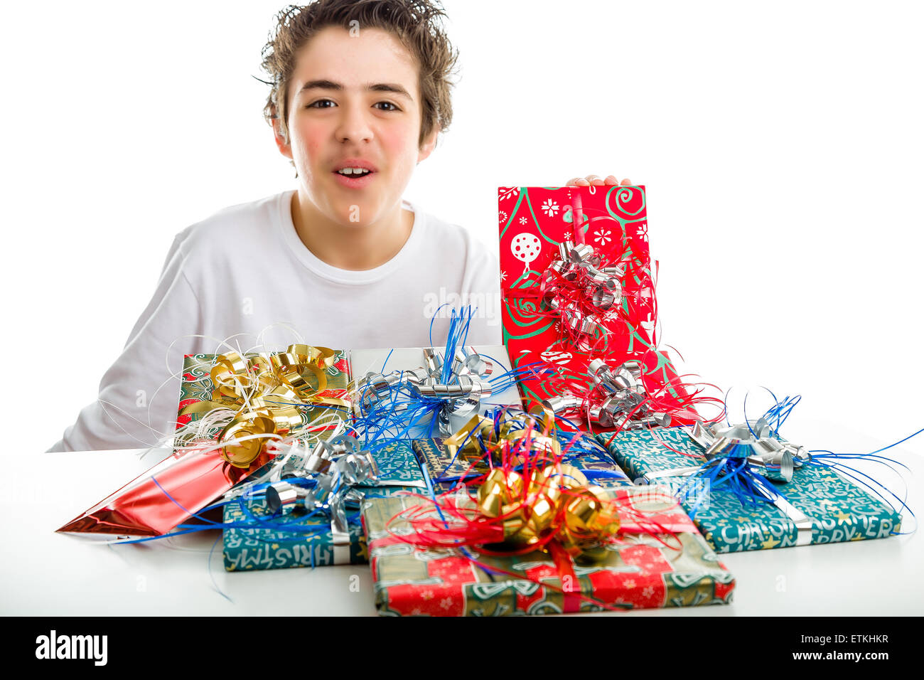 A happy boy smiles receiving several Christmas gifts in funny packages ...