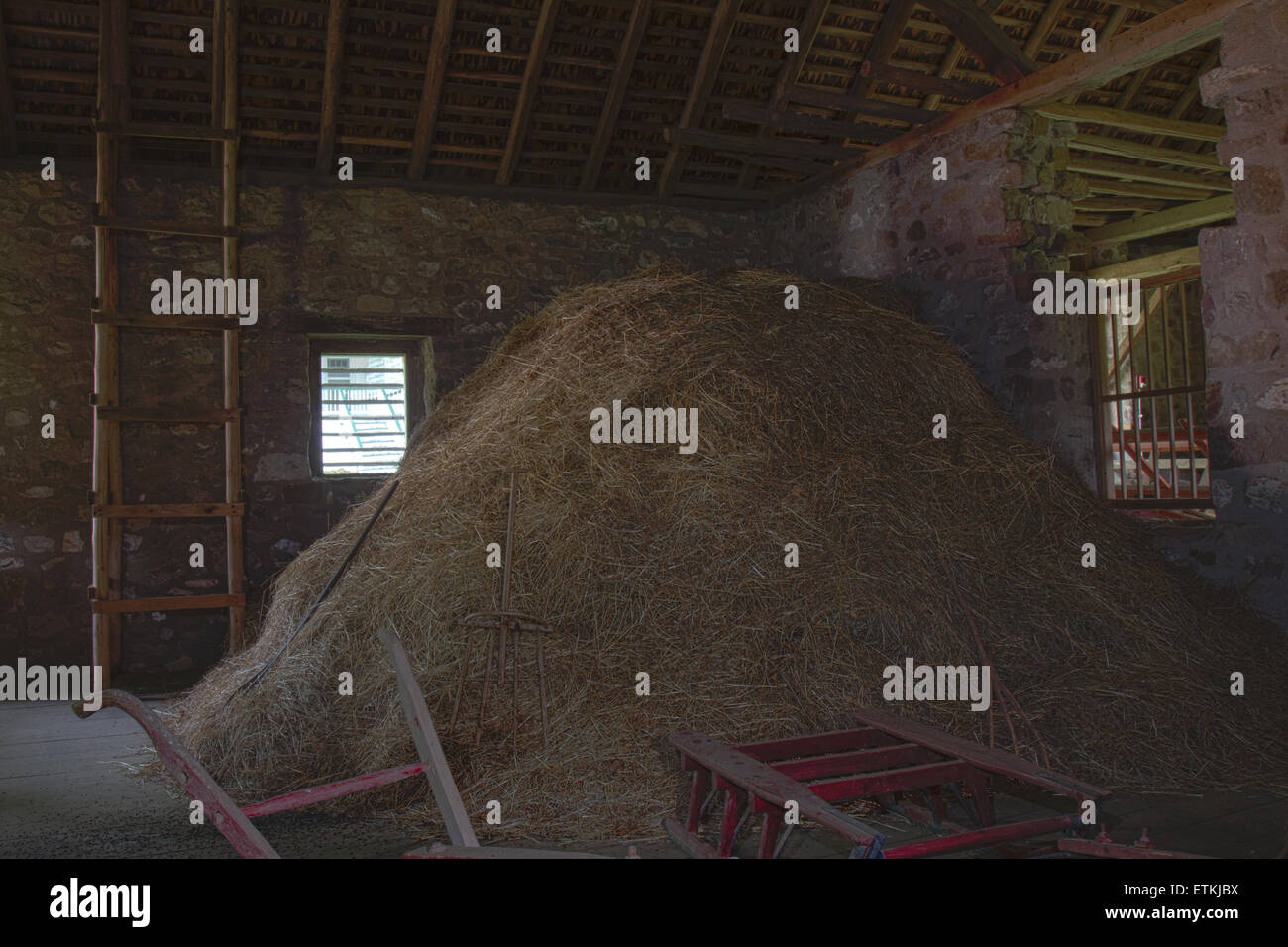 Haystack in old stone and wood barn with tools and wagons Stock Photo ...