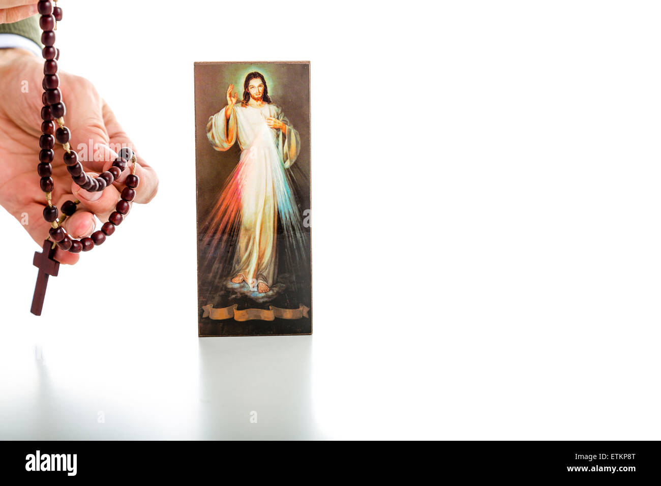 Hand offering brown Rosary beads and a picture of the Merciful Jesus ...