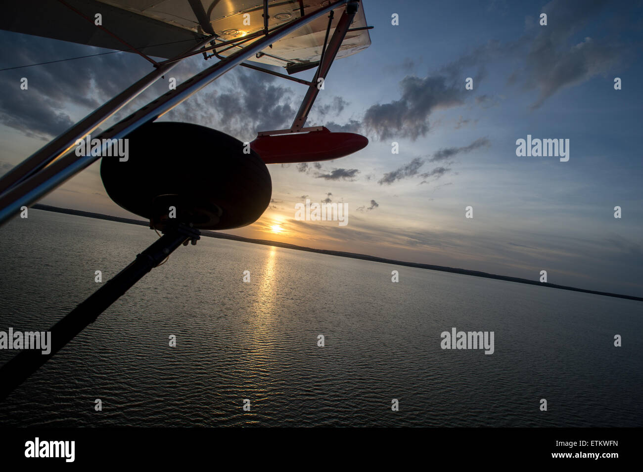 Wheel of seaplane while flying above water at sunset in Southeastern ...