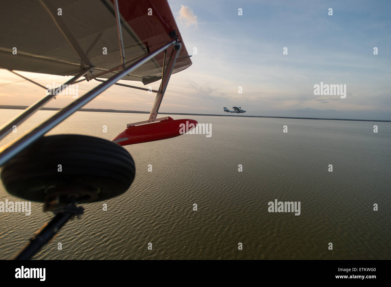 View of seaplane's wheel and wing with another plane seen in the ...