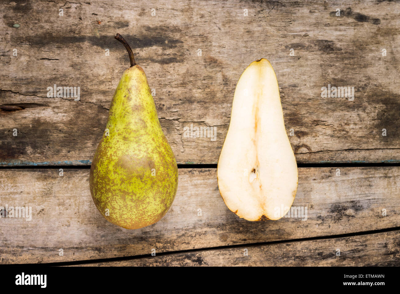 Full and cut in half pear fruit on wooden background. Top view image ...