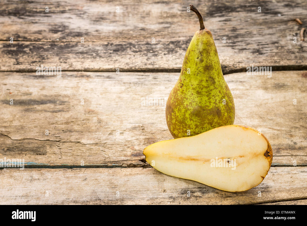 Full and cut in half pear fruit on wooden background with copy space ...