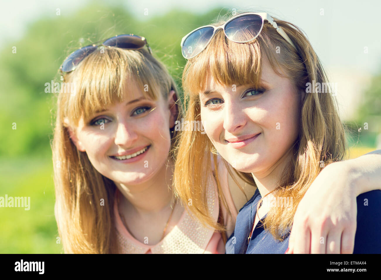 Pretty twins girls having fun at outdoor summer park. Young smiling ...