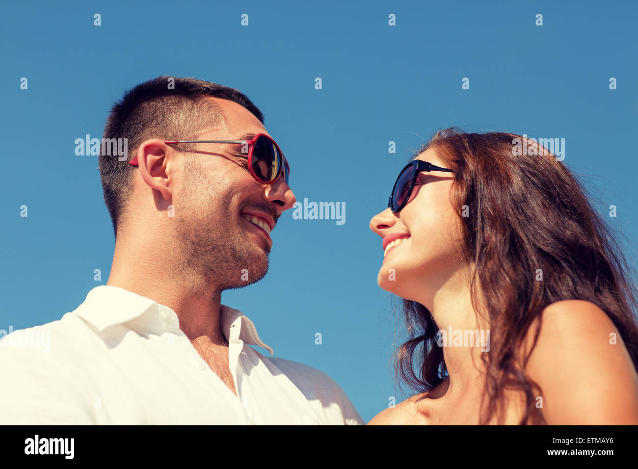 smiling couple over blue sky background Stock Photo - Alamy